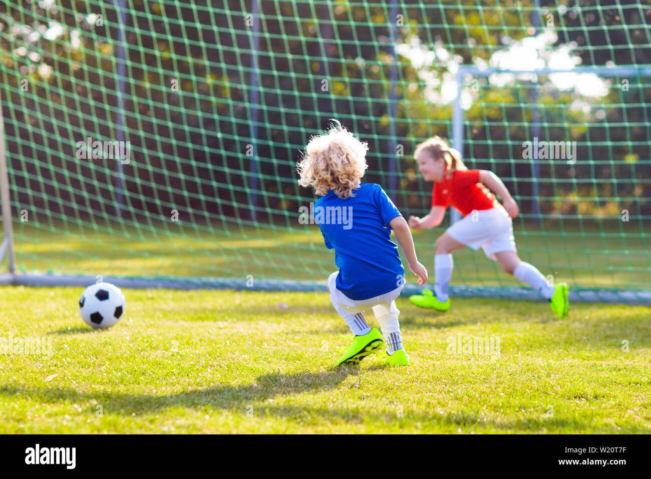 Kids play football on outdoor field. Children score a goal at soccer ...