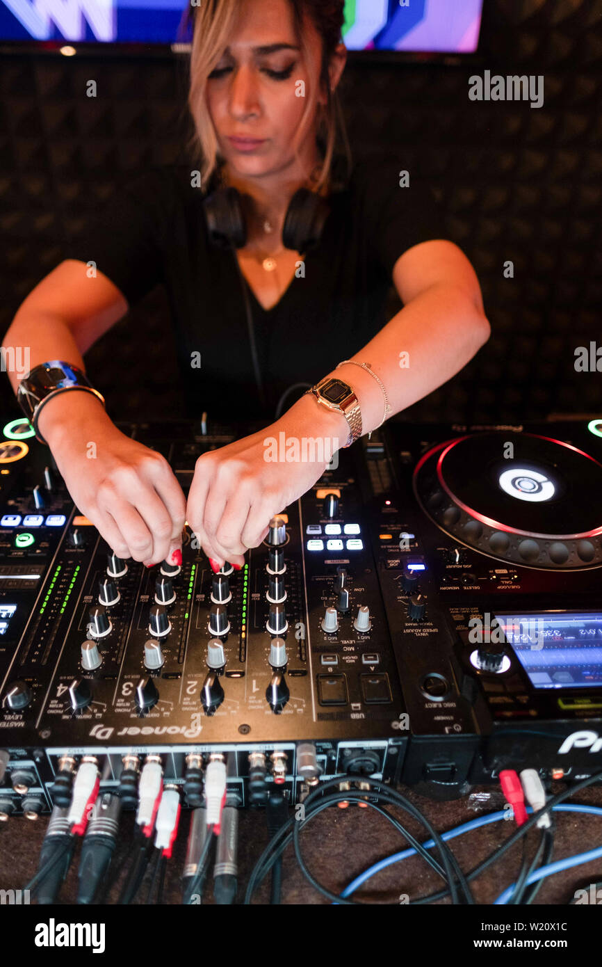 blonde woman DJ playing and mixing modern dance music in a club during ...