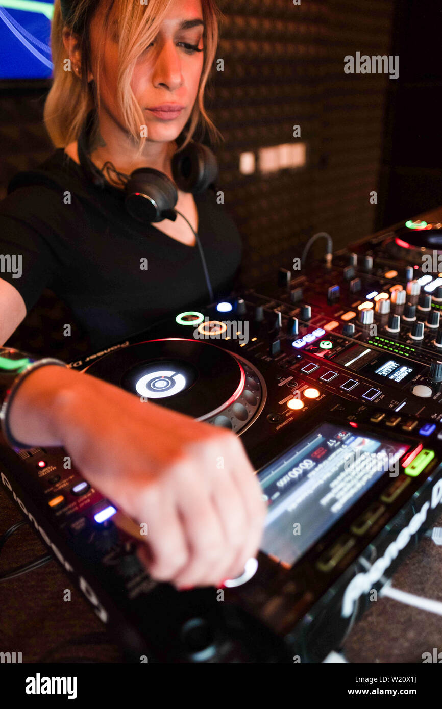 blonde woman DJ playing and mixing modern dance music in a club during ...