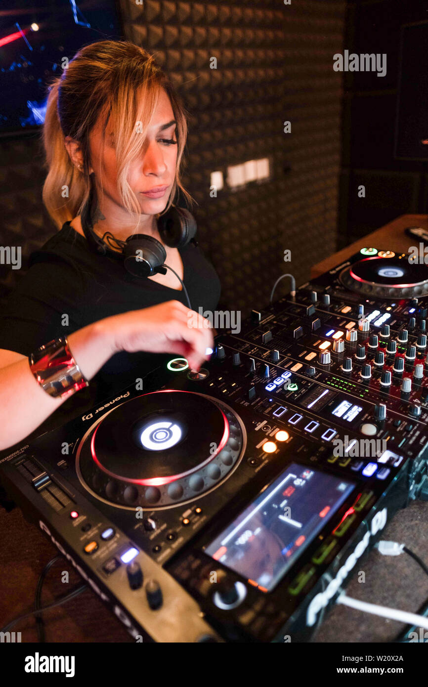 blonde woman DJ playing and mixing modern dance music in a club during ...