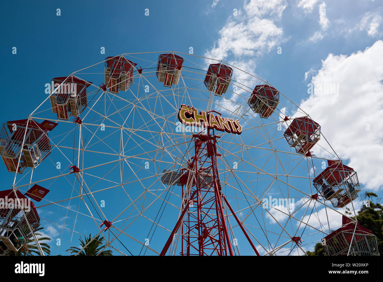 Red Ferris wheel against a blue vibrant sky sun flare during the 2019 ...