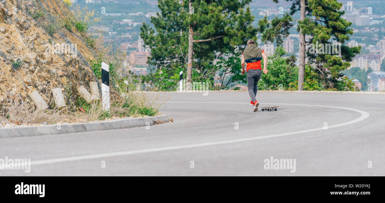 Tall young male fit longboarder jumping off his longboard while trying ...