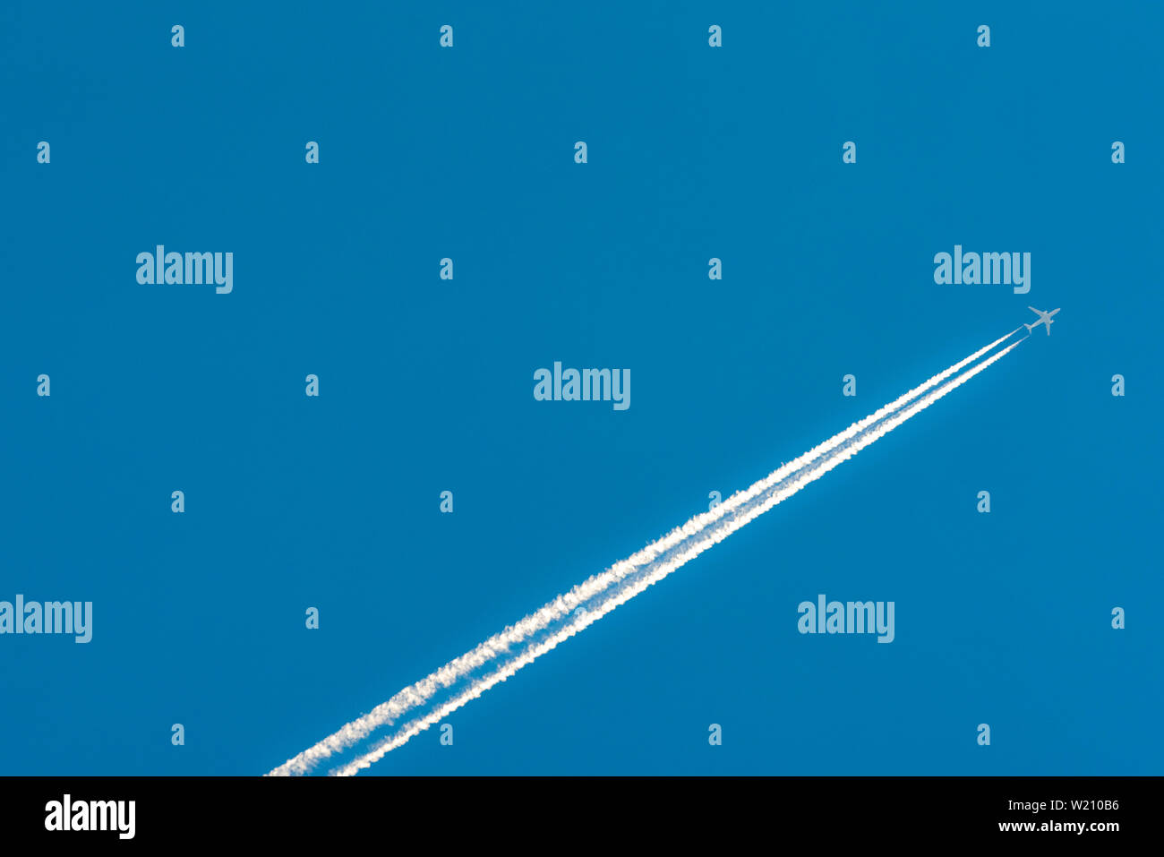 Airplane with white condensation tracks. Jet plane on clear blue sky ...