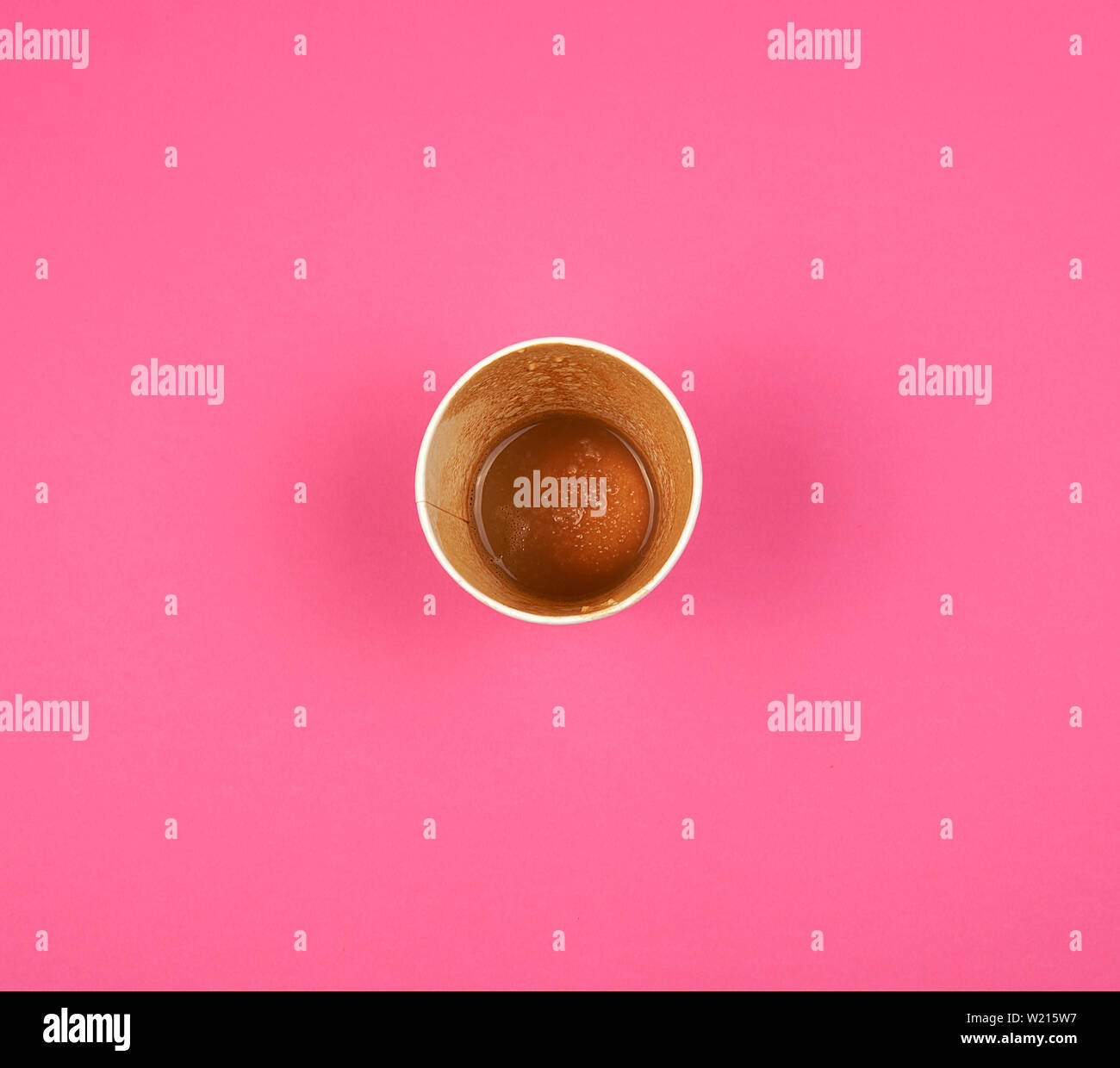 empty used red paper cup from under coffee stands on pink background ...