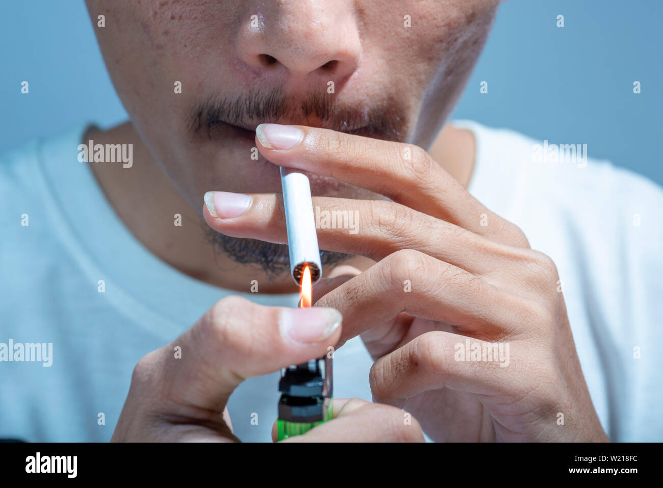 Man with lighter lit a cigarette and smokes on gray background Stock ...