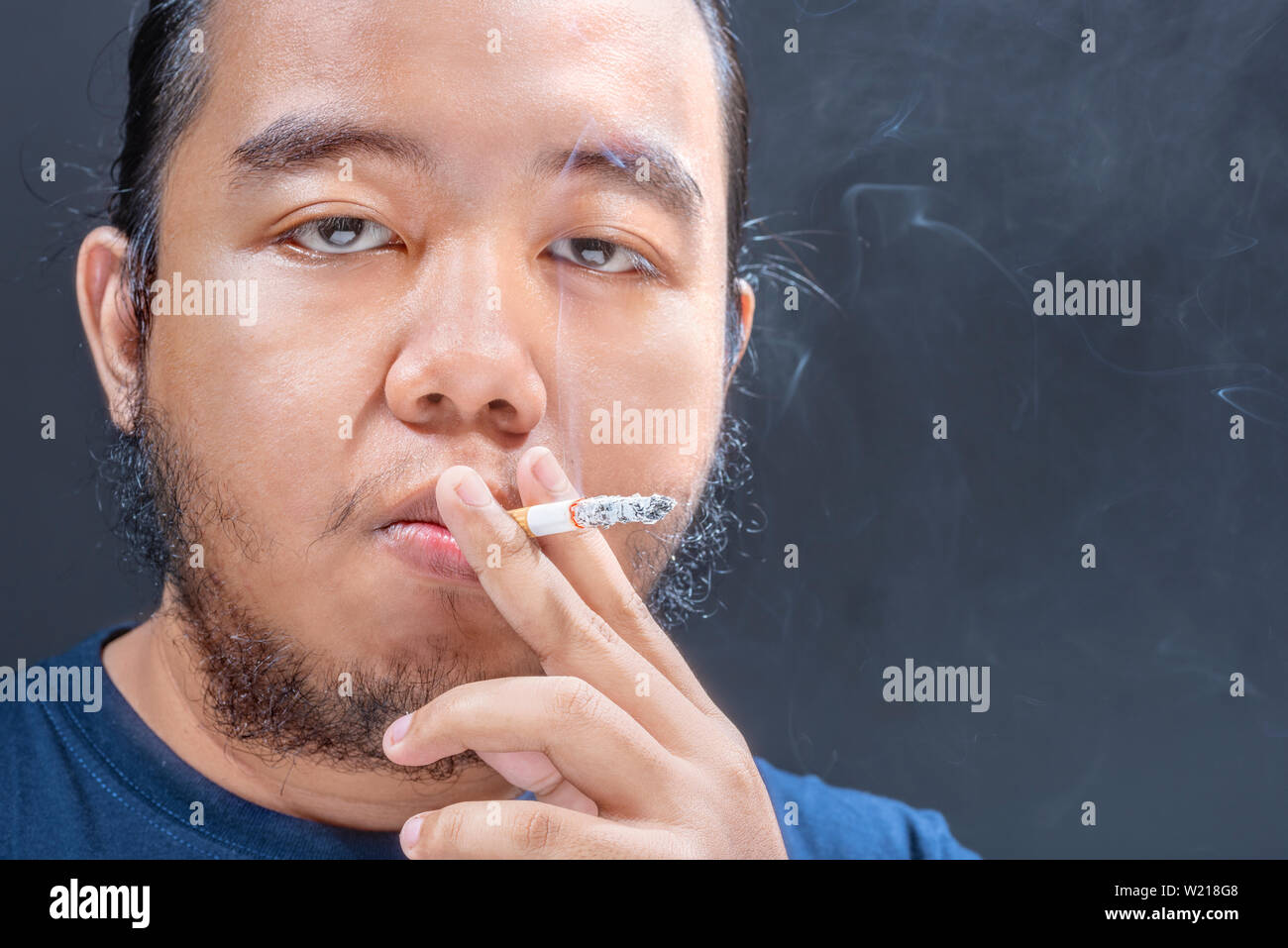 Asian man smoking cigarette on gray background Stock Photo - Alamy
