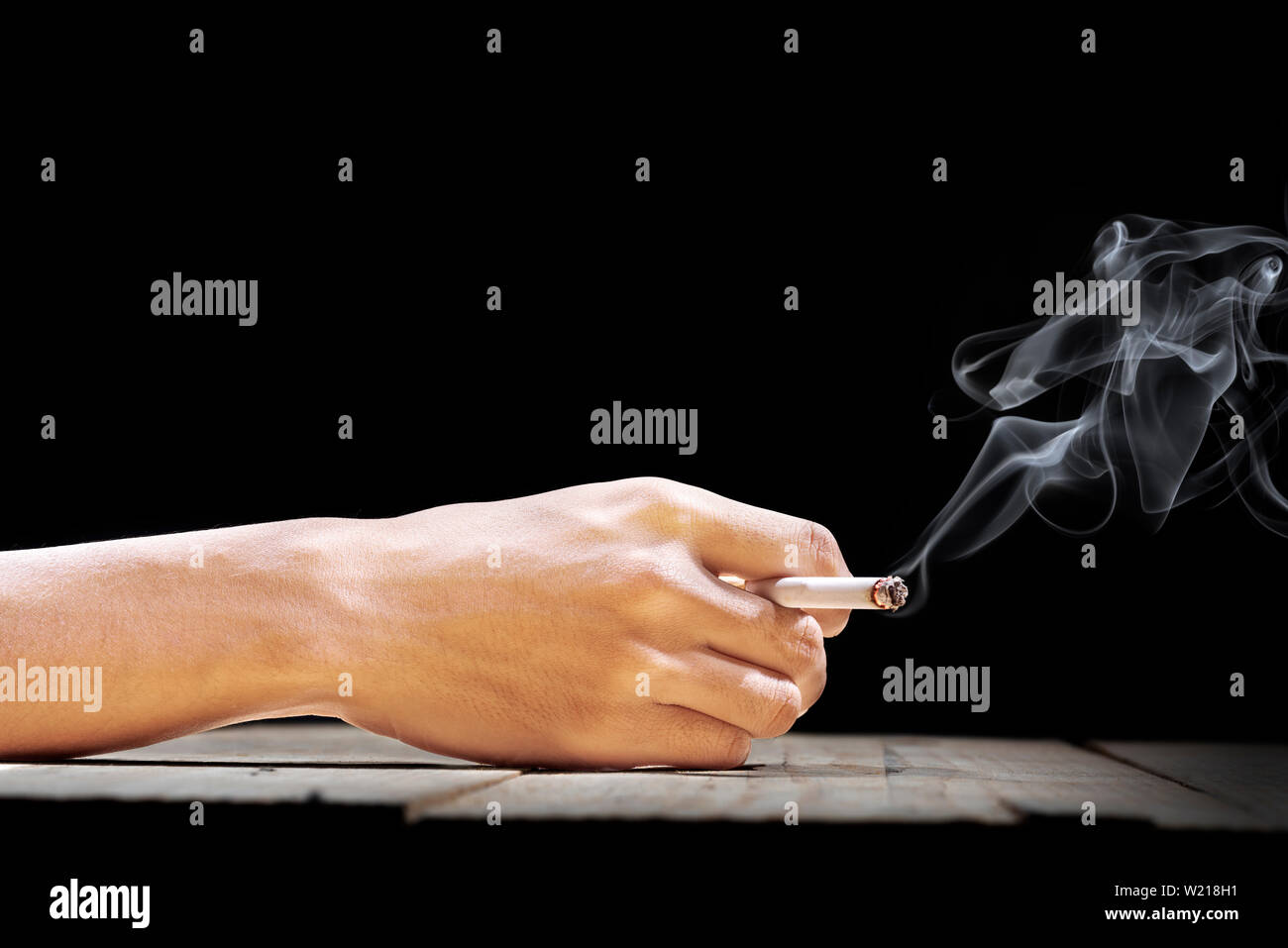 Hand holding a cigarette on wooden table with black background Stock ...