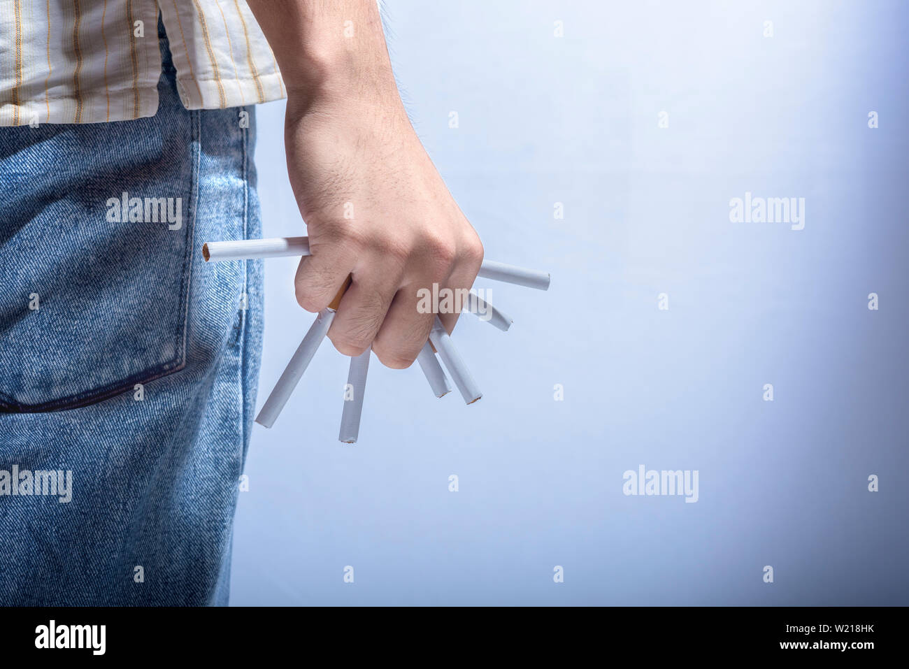 Man standing while smashed some cigarettes on his hand over gray ...
