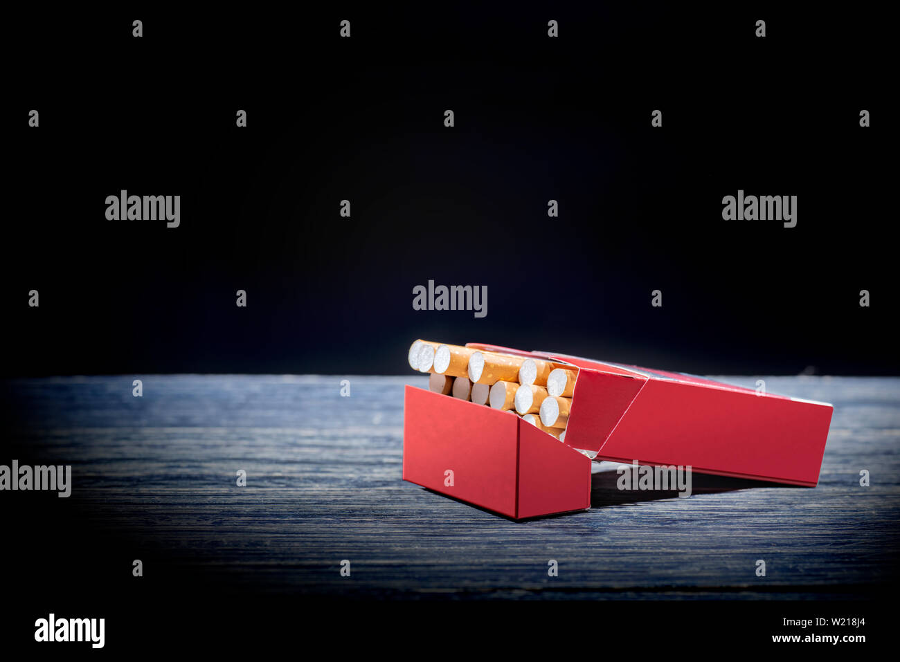 Red pack of cigarettes on wooden table with black background Stock ...
