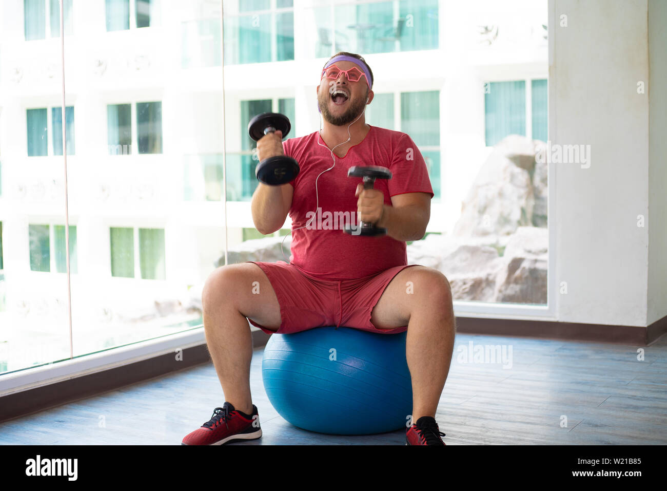 Funny fat male in pink glasses and in a pink t-shirt is engaged with ...