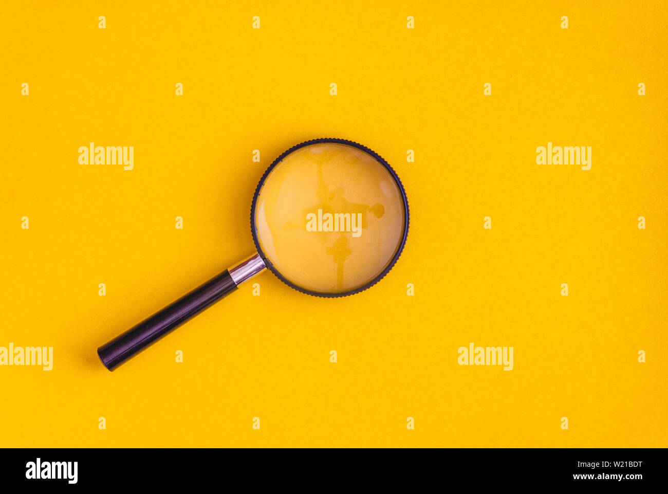 Magnifier lies on yellow and blue background. View from above. Flat lay ...