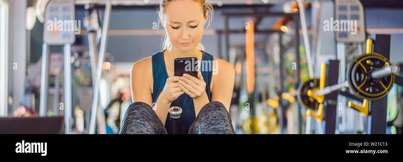 Young woman using phone while training at the gym. Woman sitting on ...