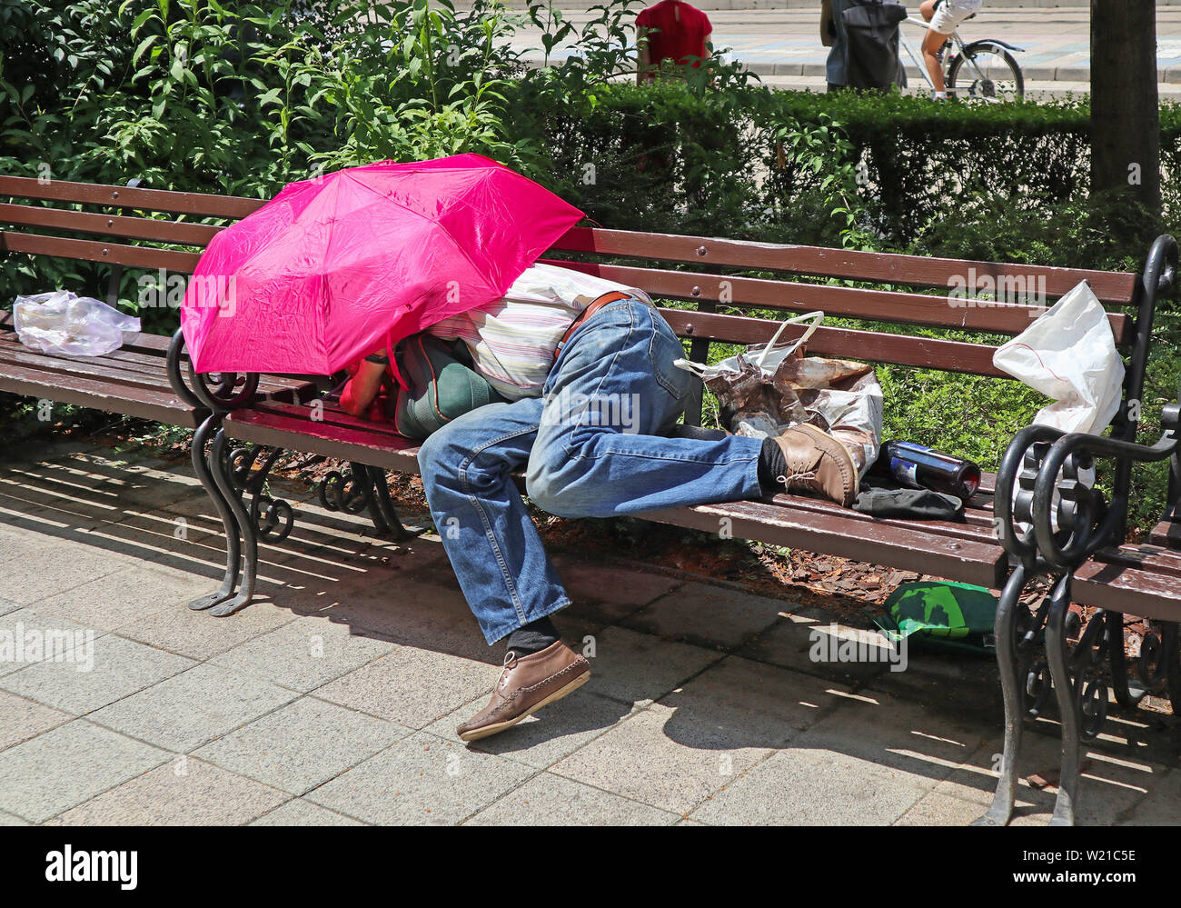 Homeless man is sleeping on a bench in the city Stock Photo - Alamy