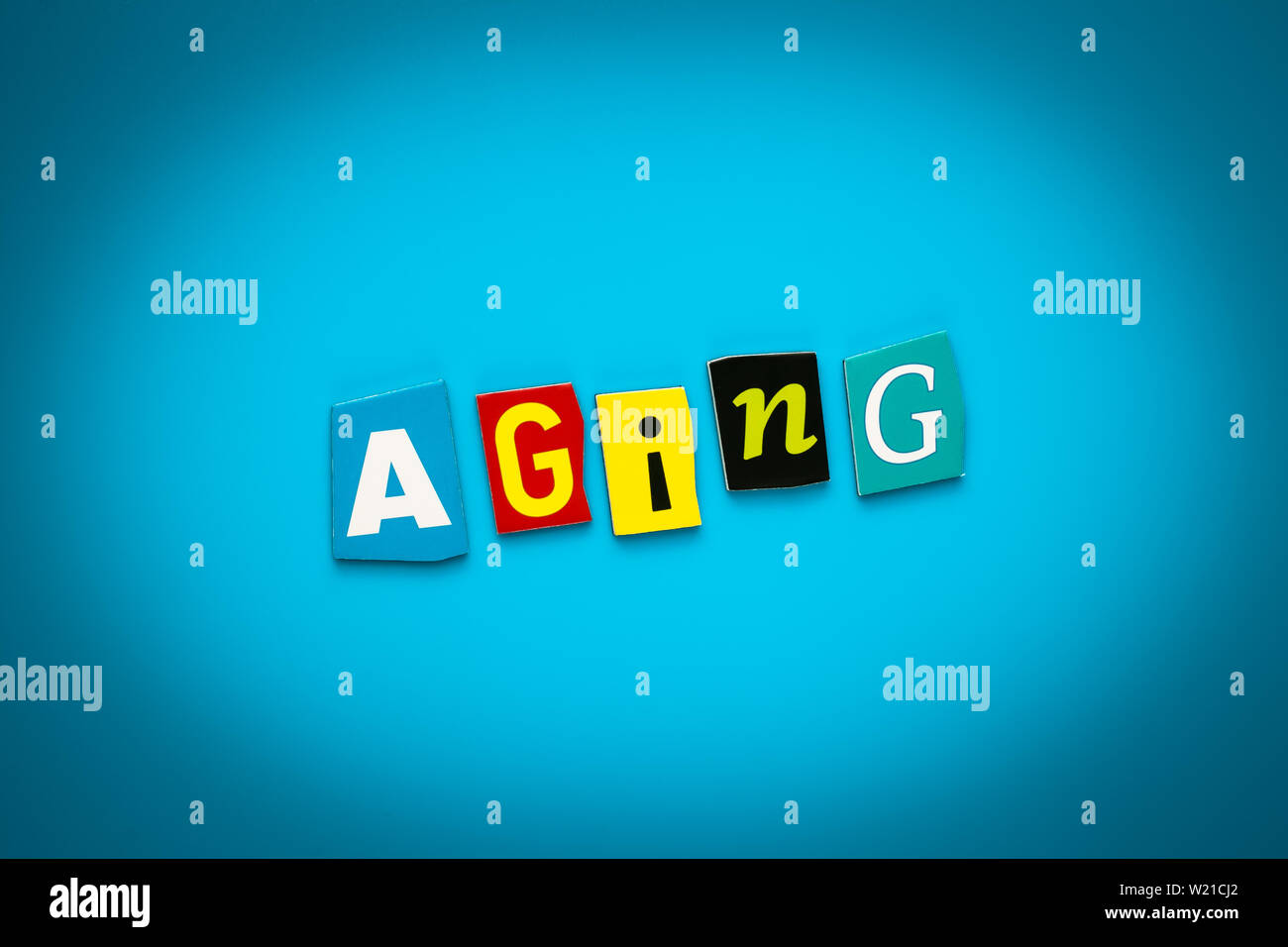 Single word - aging - from cut colored letters on blue background ...