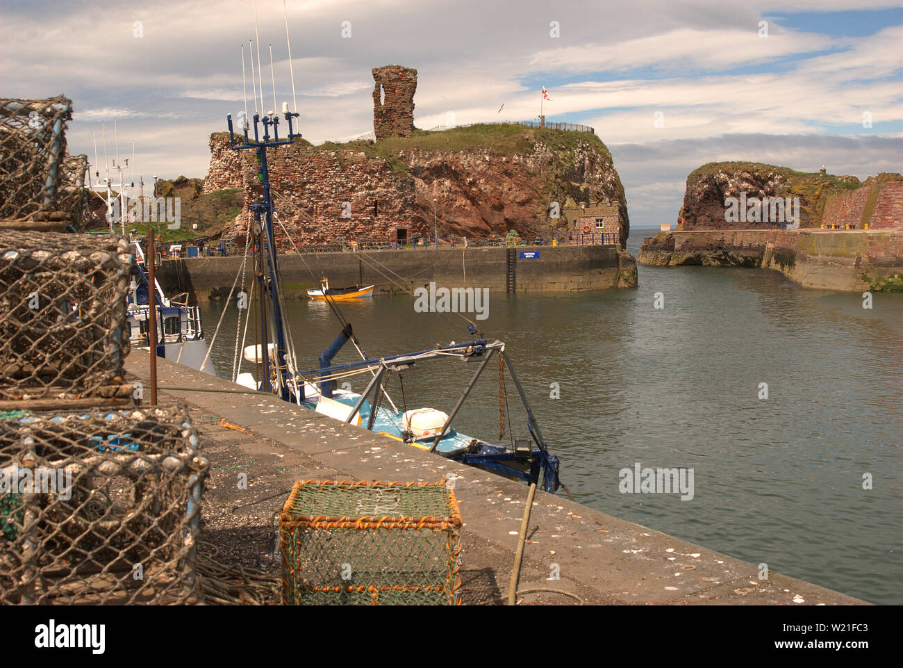 Dunbar castle ruins at entrance to Dunbar harbour with fishing boats ...