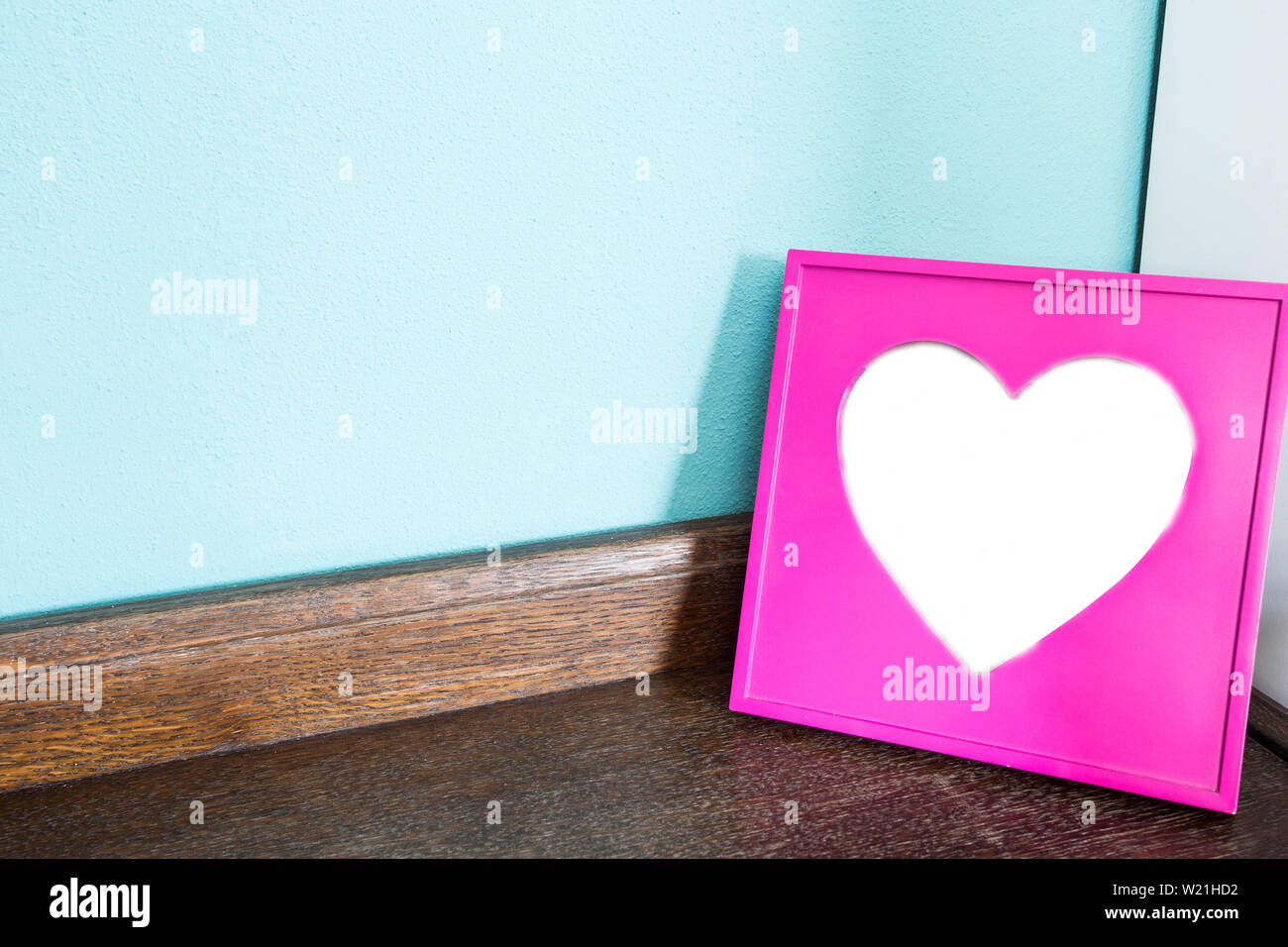 Pink heart picture frame on wood table with blue wall background, space ...