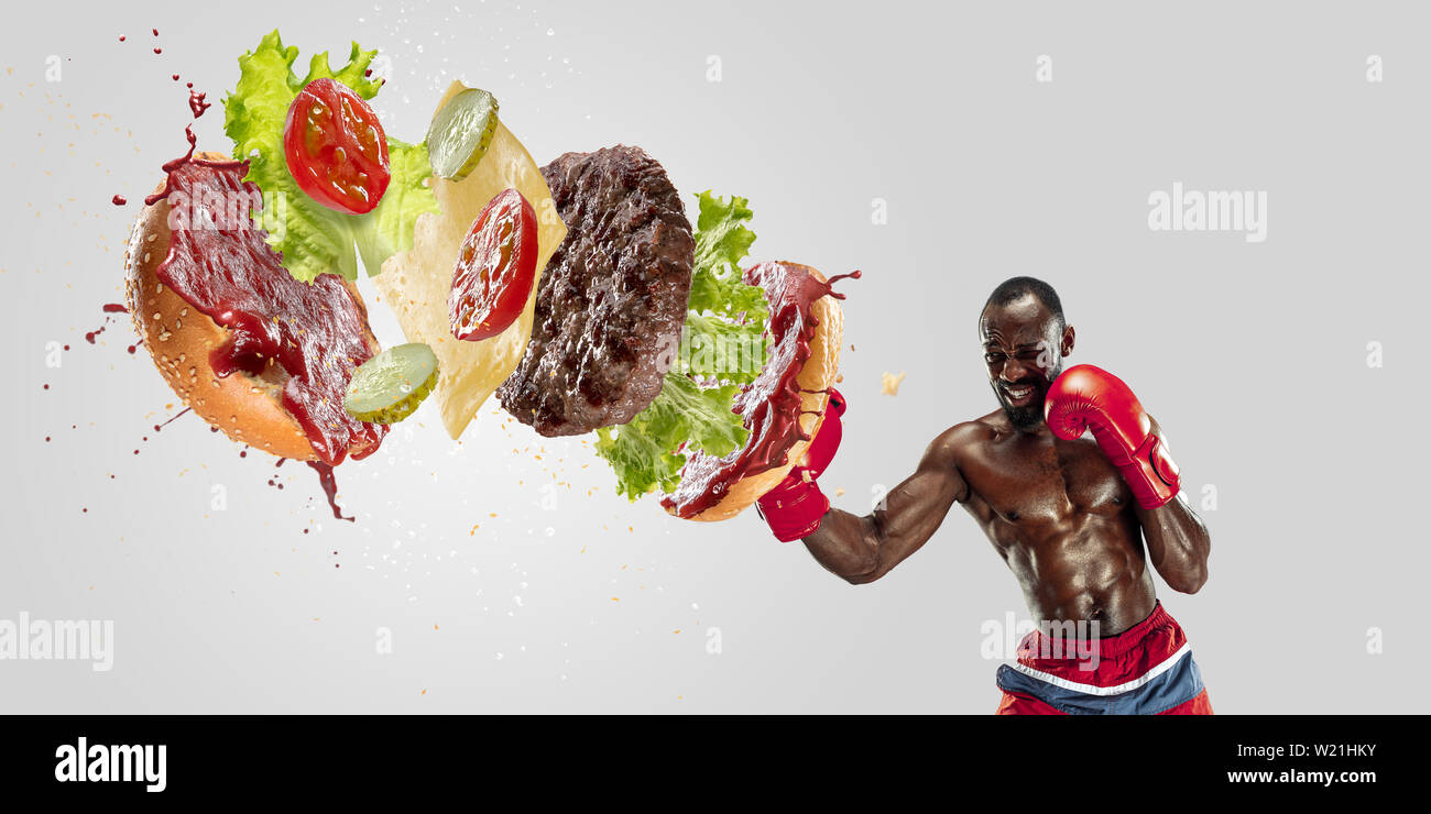 Fight the fast food. Burger's crashing by the boxer isolated on white ...