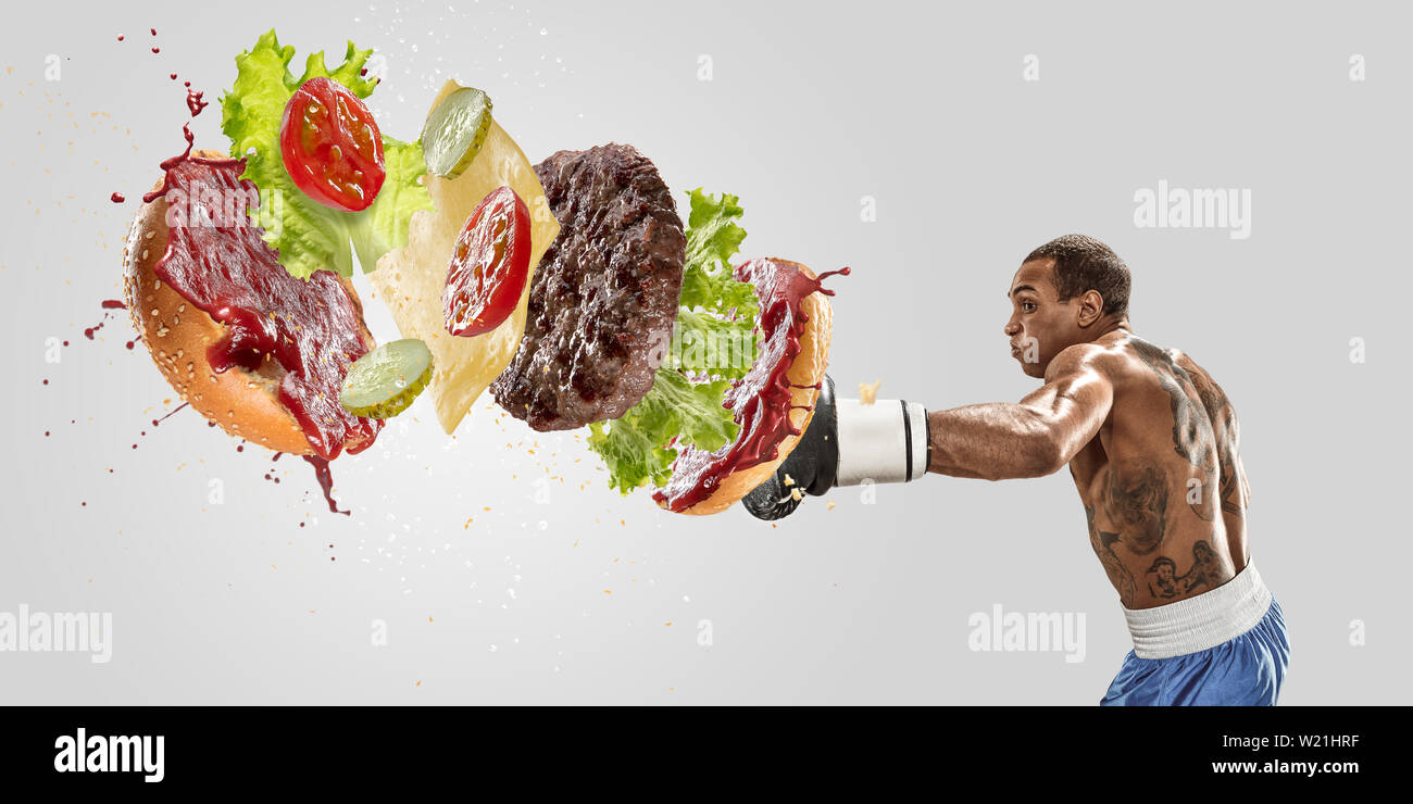 Fight the fast food. Burger's crashing by the boxer isolated on white ...
