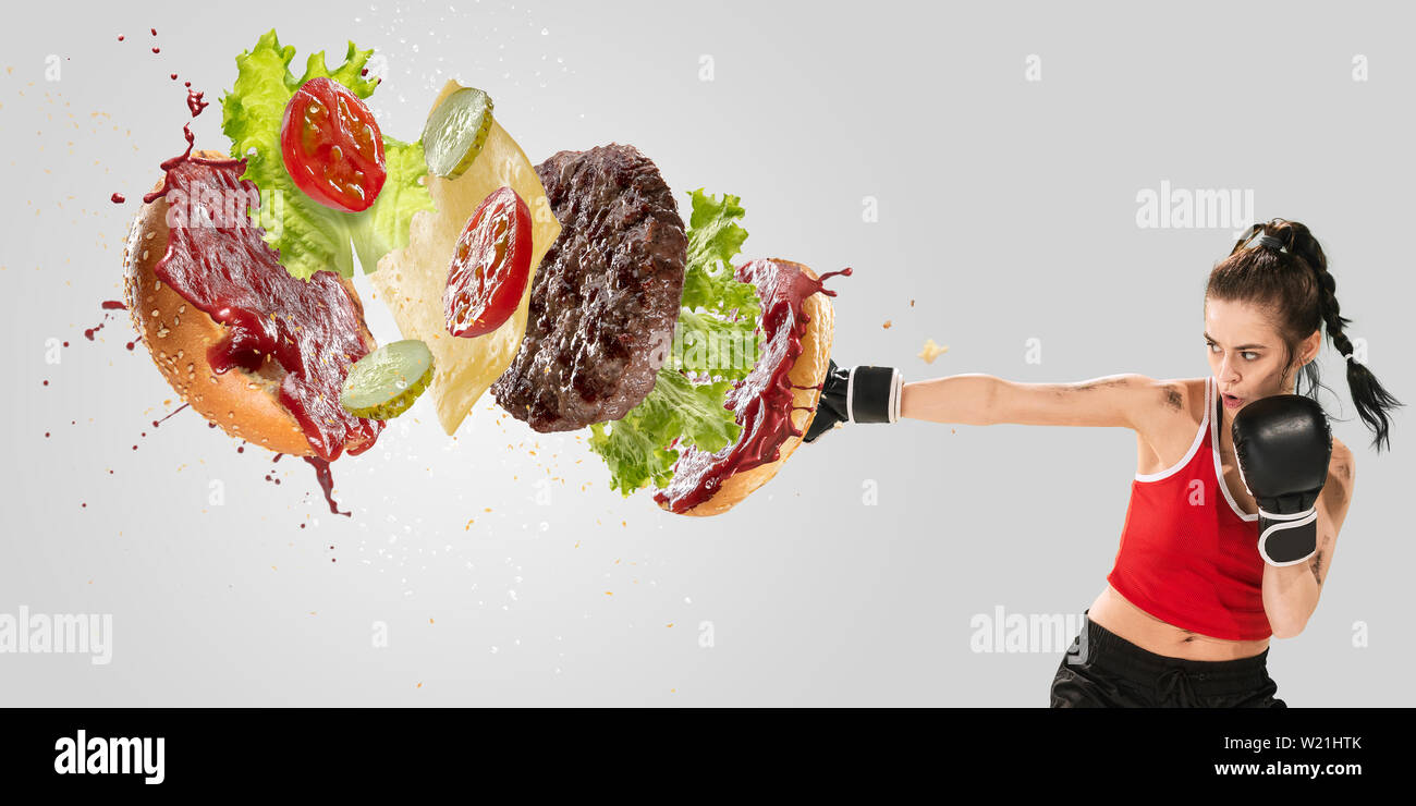 Fight the fast food. Burger's crashing by the boxer isolated on white ...