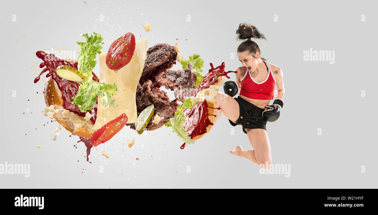 Fight the fast food. Burger's crashing by the boxer isolated on white ...