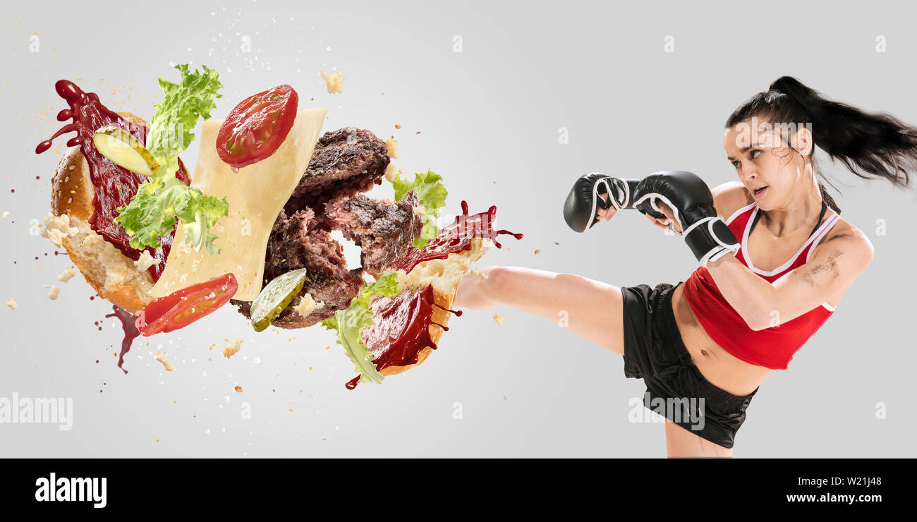 Fight the fast food. Burger's crashing by the boxer isolated on white ...
