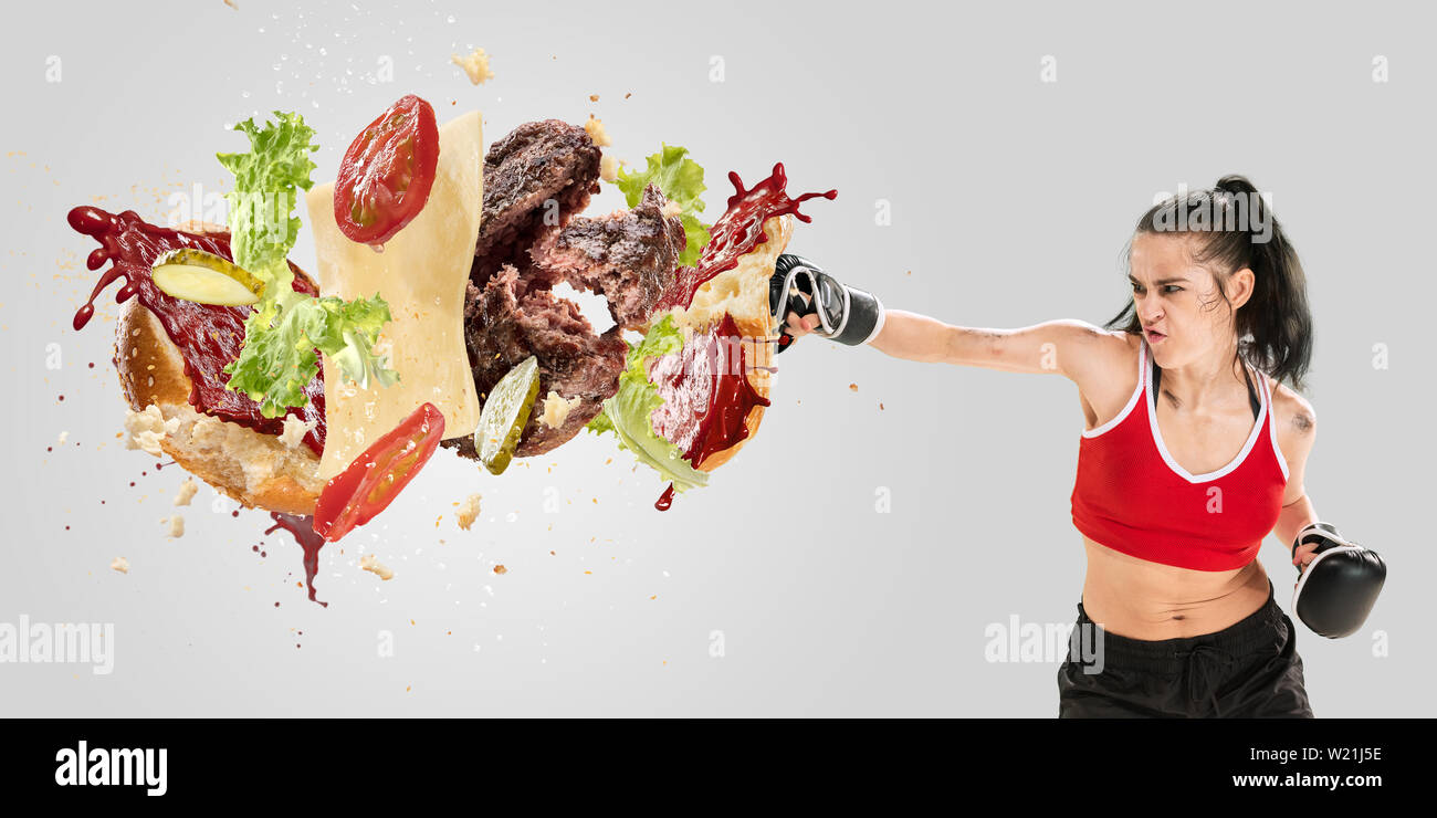 Fight the fast food. Burger's crashing by the boxer isolated on white ...