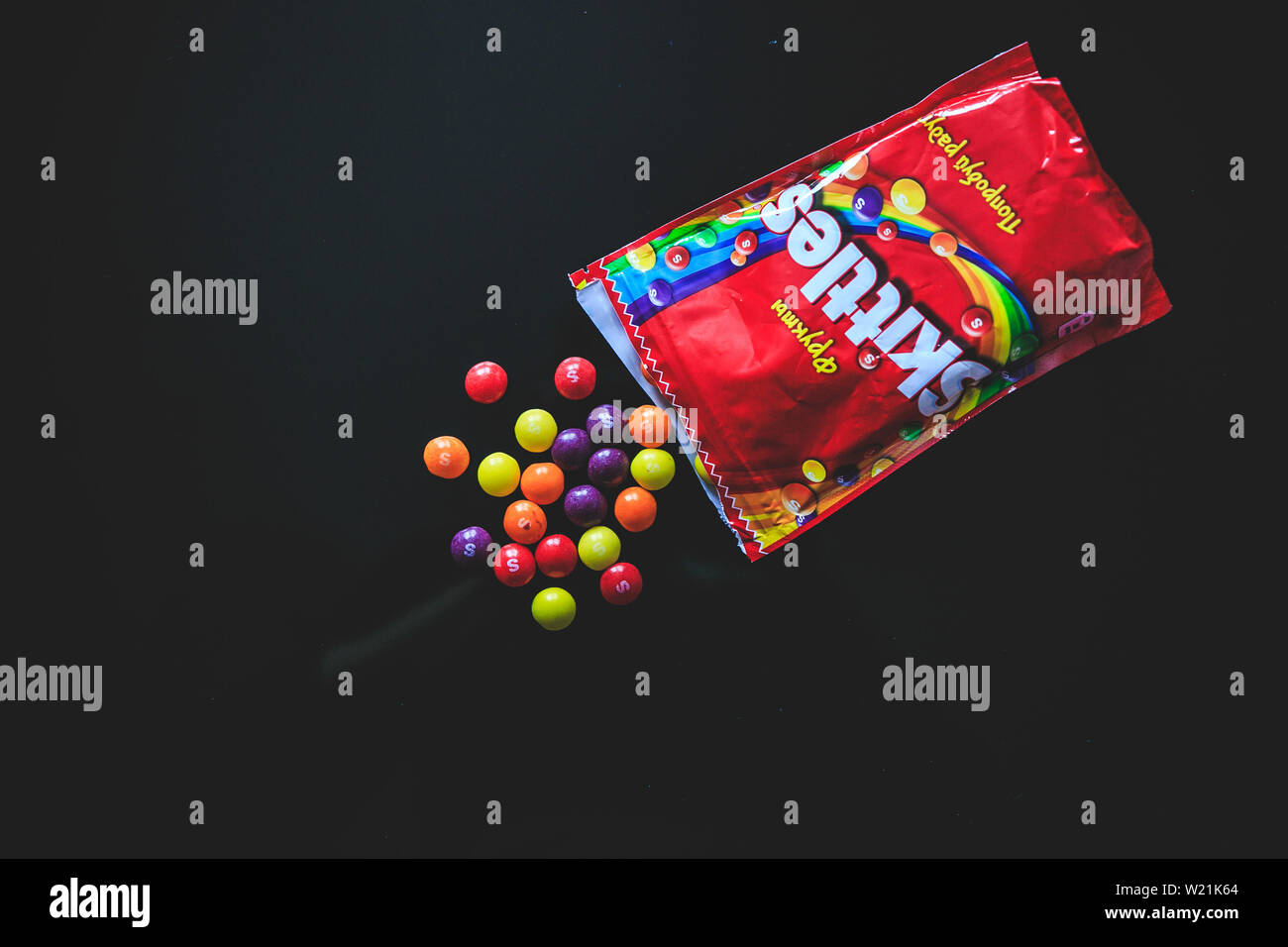 MOSCOW, RUSSIA - JULY 5, 2019: Colorful skittles candies on a black ...