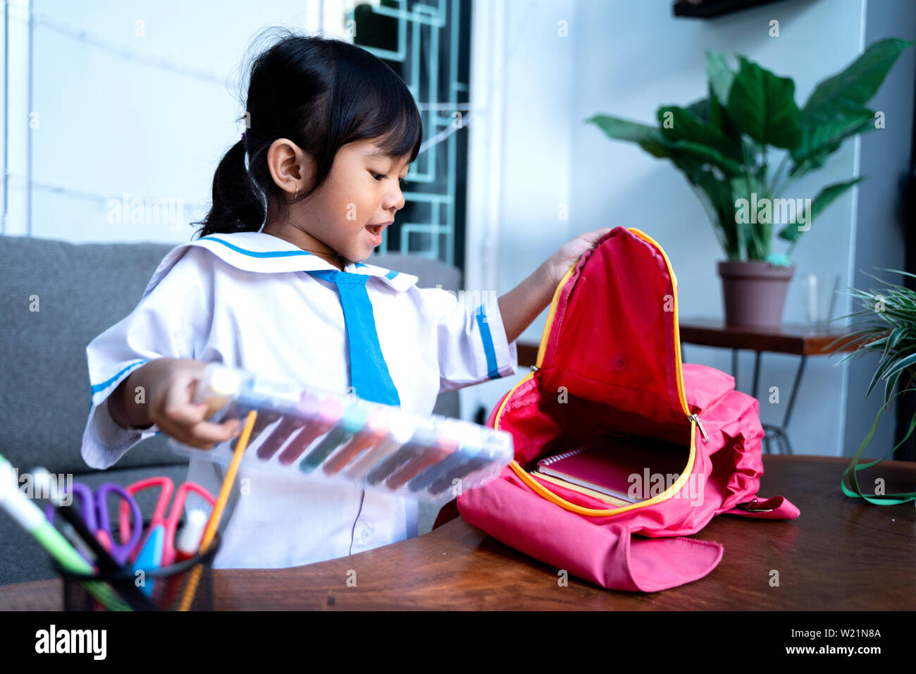 independent young kindergarten student preparing her own stuff before ...