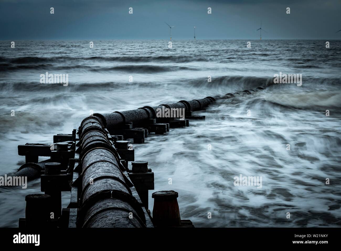 Corroded iron pipe, sewage pipe in the sea surf under a dark sky, Blyth ...