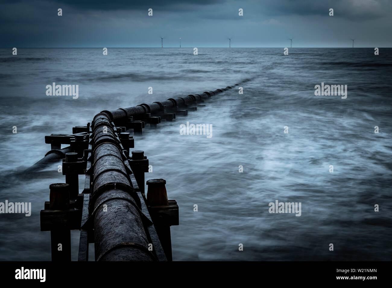 Sewage pipe in the sea surf under a dark sky hi-res stock photography ...