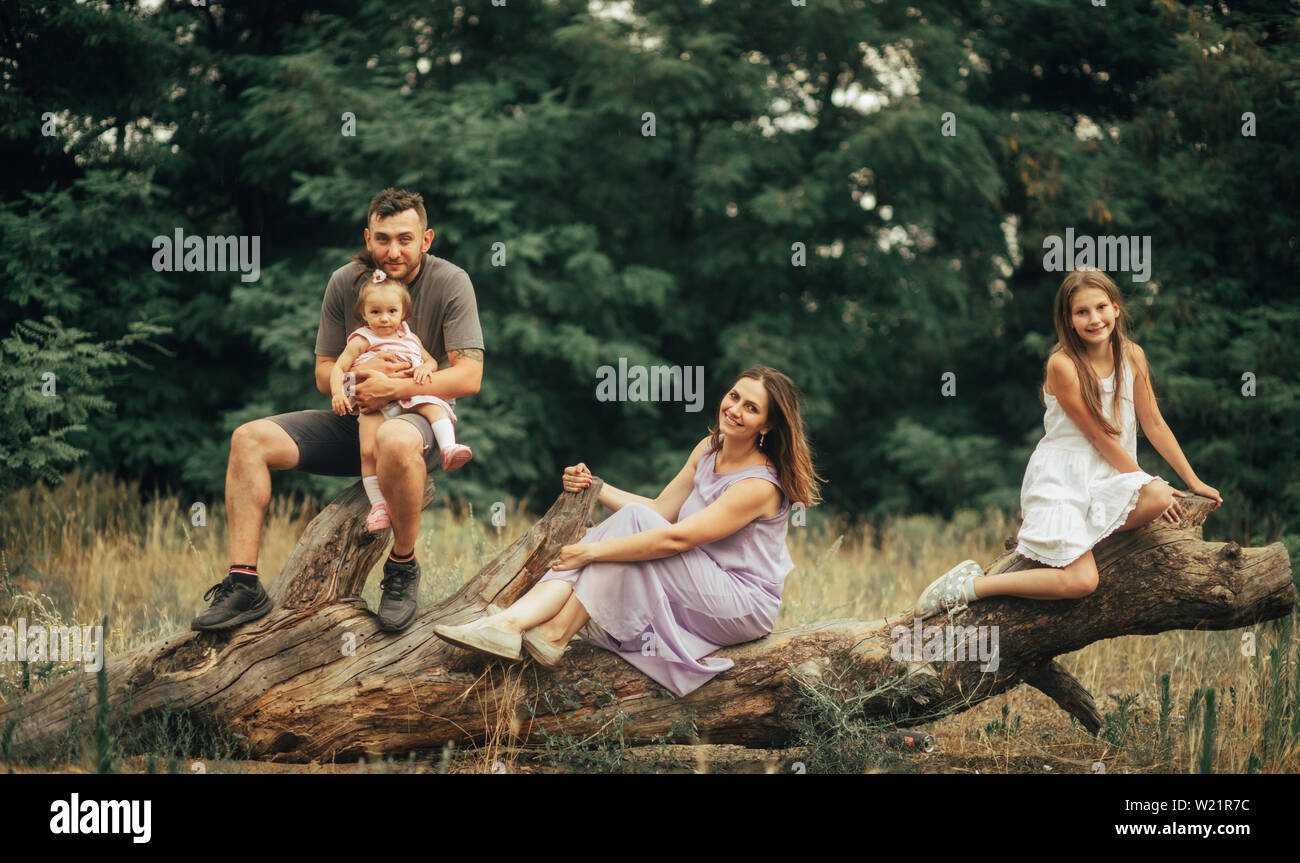 Family resting on a fallen tree trunk while walking in the forest Stock ...