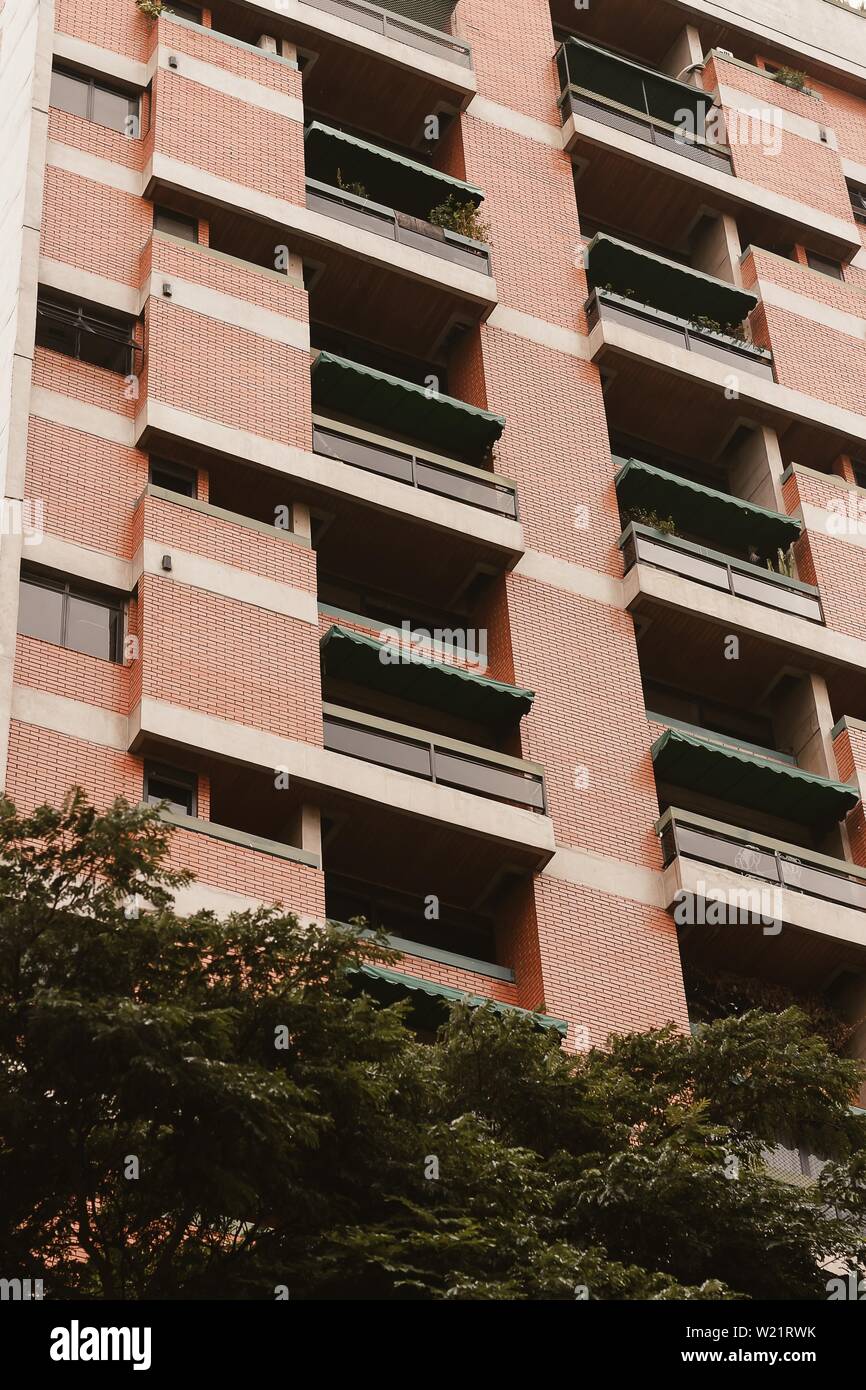 Low angle shot of a tall apartment building with greenery below Stock ...