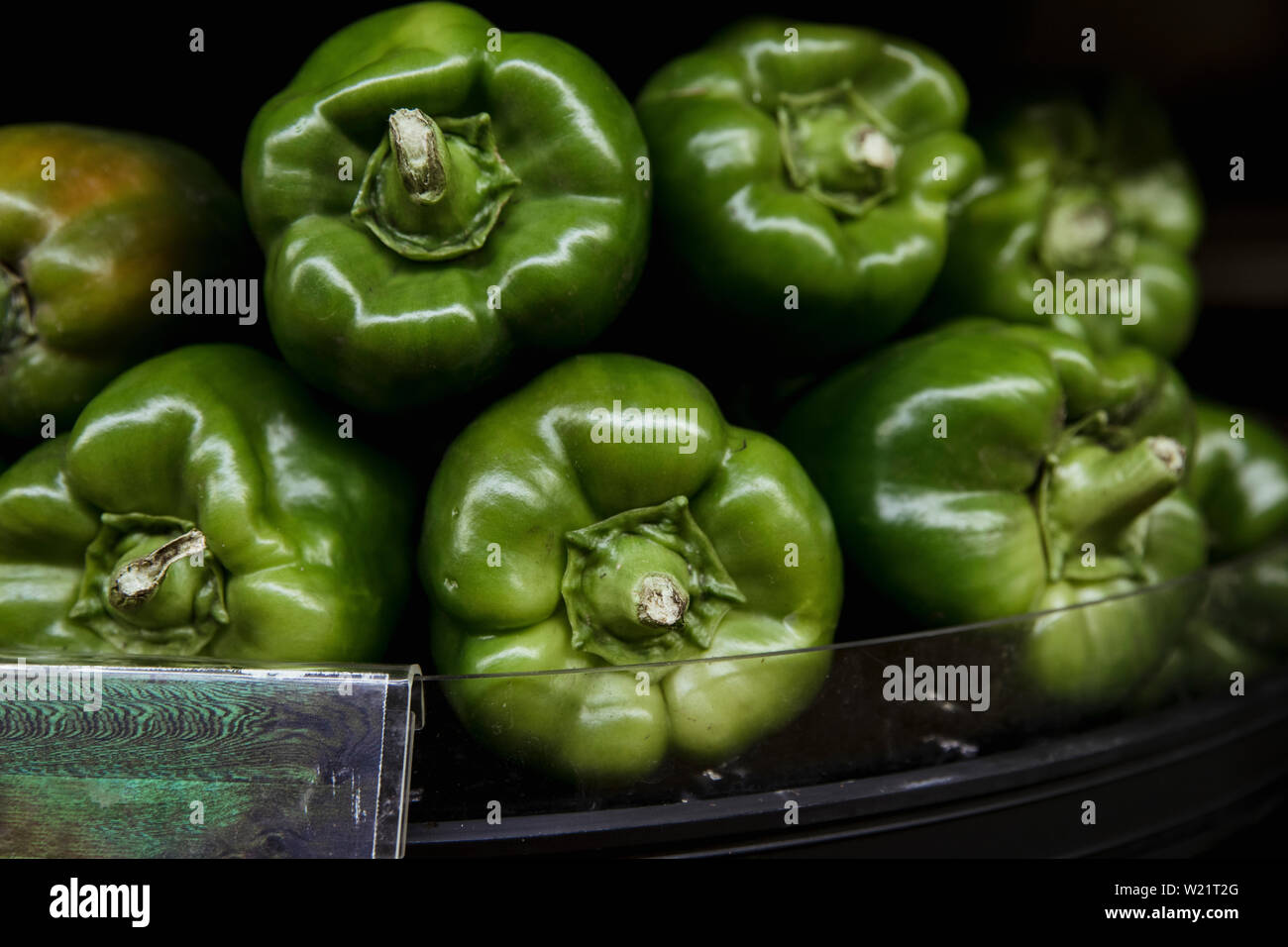 A close-up shot of an abundance of fresh green peppers on display at a ...