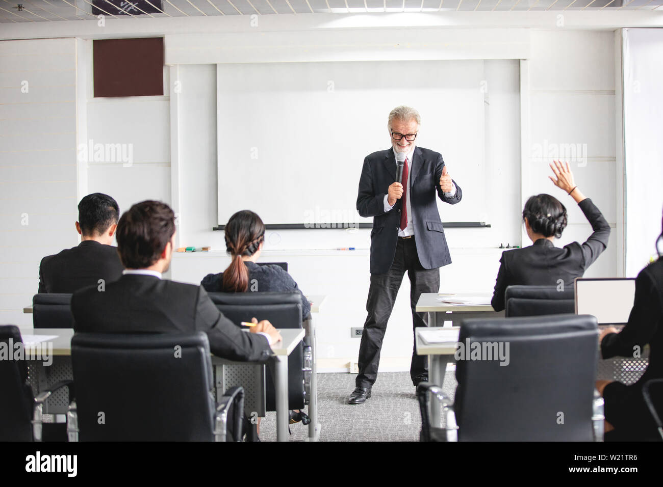 Business Audience raising hand up while businessman is speaking in ...