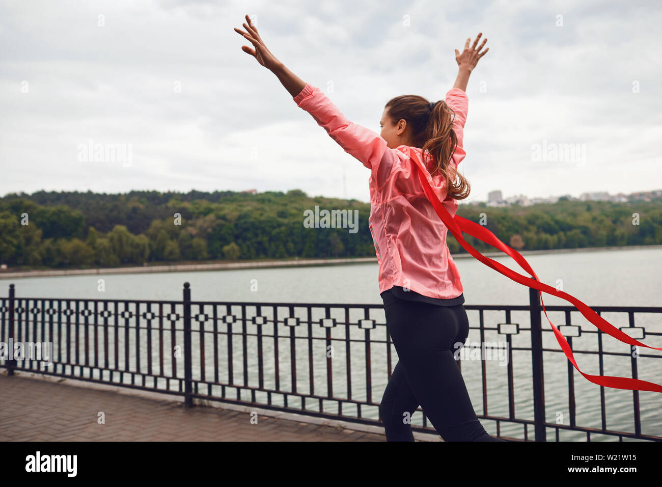Girl runner finishes the race with a red ribbon. Winner in the sport ...