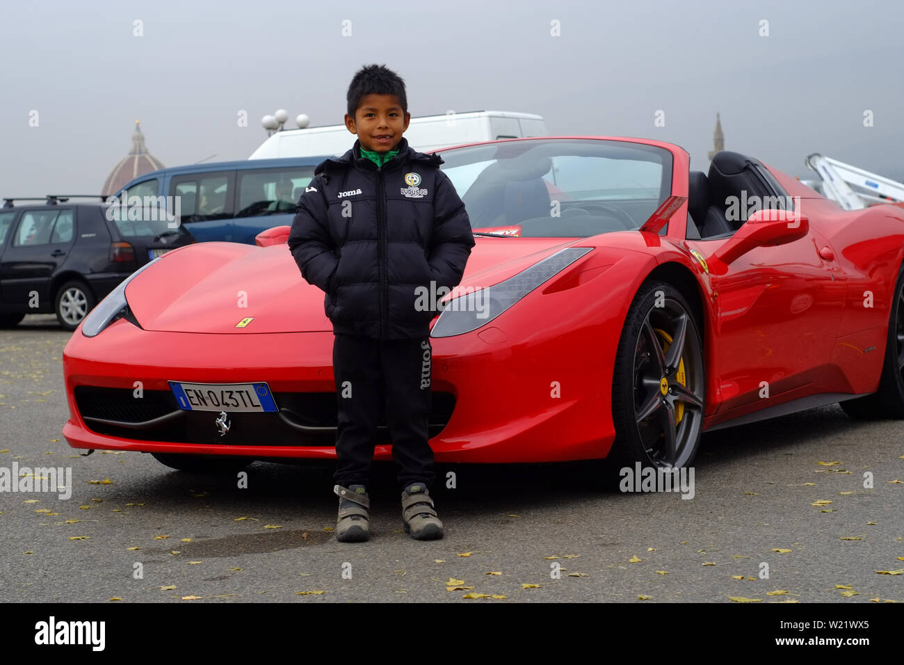 Red luxury italian Ferrari car parked with latin boy beside it. Early ...