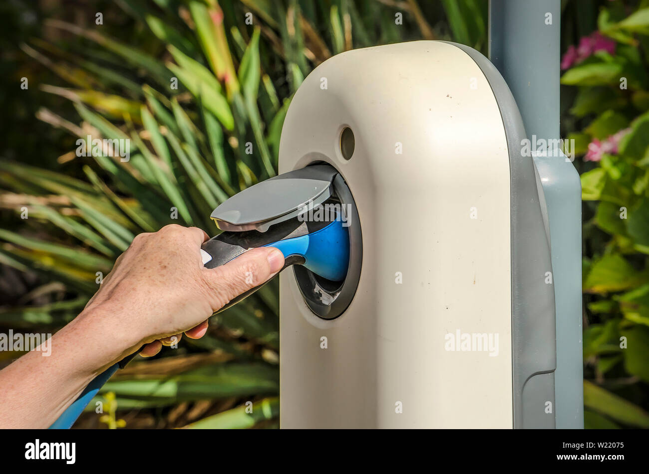 Human hand putting a blue cable of an electric car into a charging ...