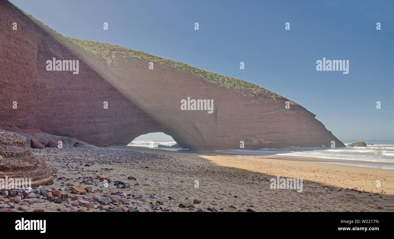Red rock formation with arch on the beach, Plage Sidi Ifni, Morocco ...