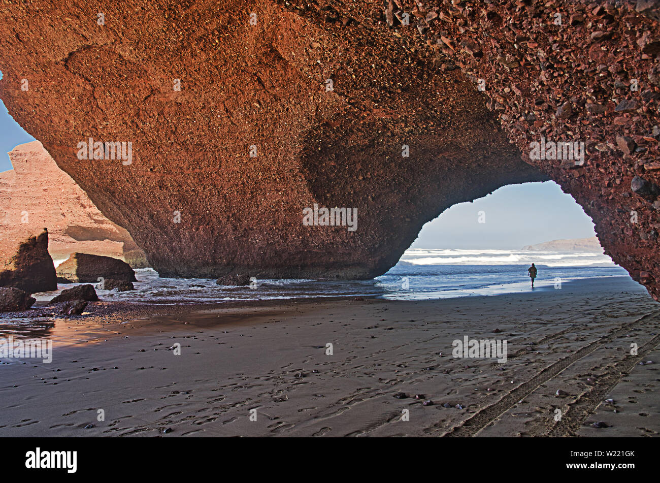 Red rock formation with arch on the beach, Plage Sidi Ifni, Morocco ...