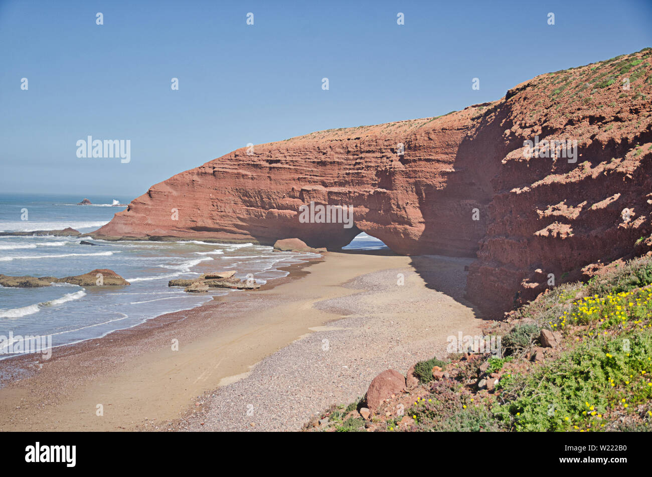 Red rock formation with arch on the beach, Plage Sidi Ifni, Morocco ...