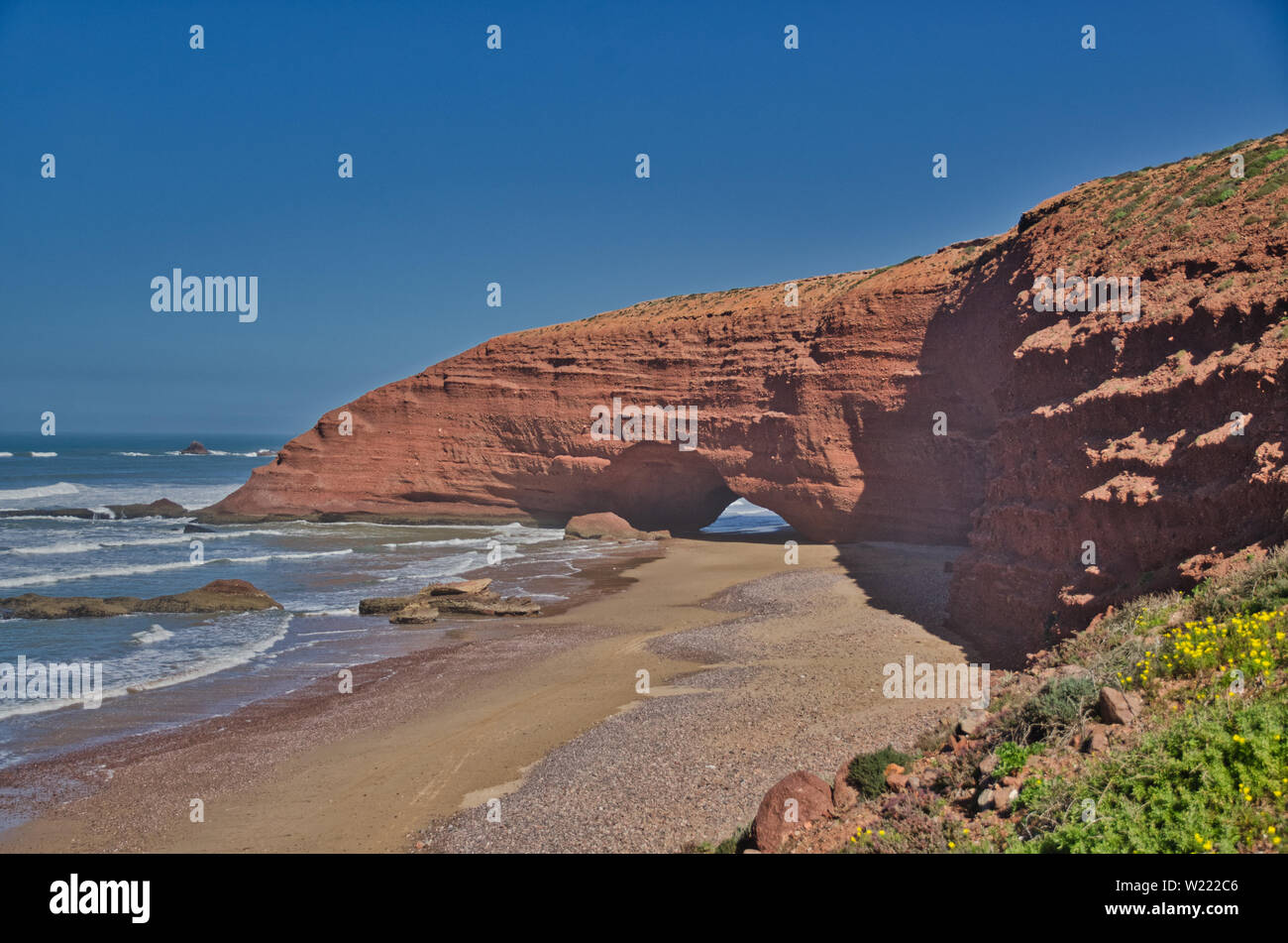 Red rock formation with arch on the beach, Plage Sidi Ifni, Morocco ...