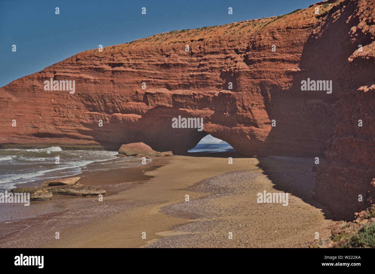 Red rock formation with arch on the beach, Plage Sidi Ifni, Morocco ...