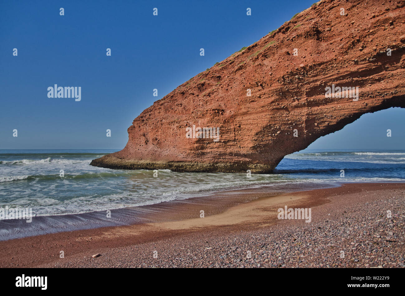 Red rock formation with arch on the beach, Plage Sidi Ifni, Morocco ...