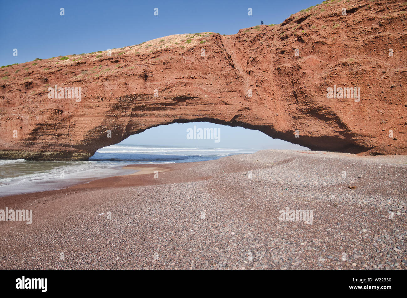 Red rock formation with arch on the beach, Plage Sidi Ifni, Morocco ...
