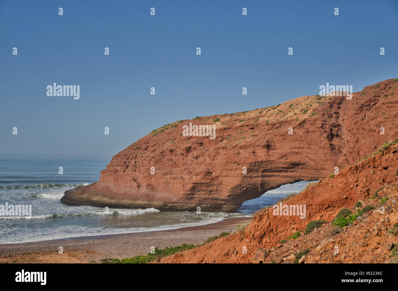 Red rock formation with arch on the beach, Plage Sidi Ifni, Morocco ...