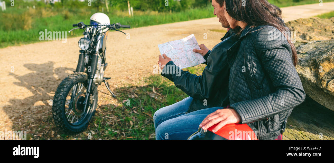 Couple sitting looking at a map with motorcycle Stock Photo - Alamy