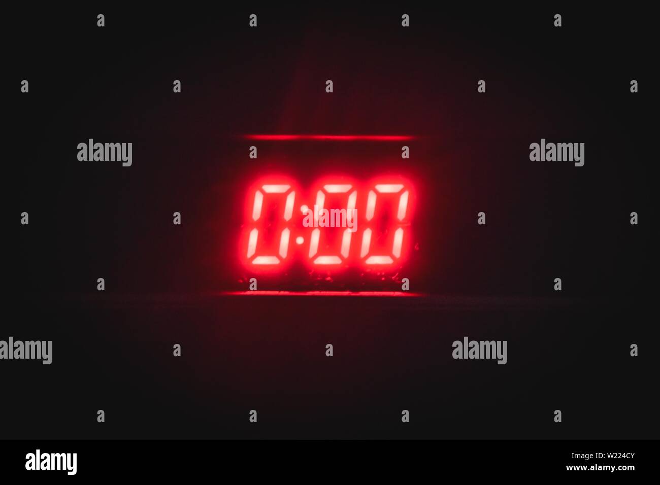 Digital clock with red neon numbers "0:00" on a dark background ...