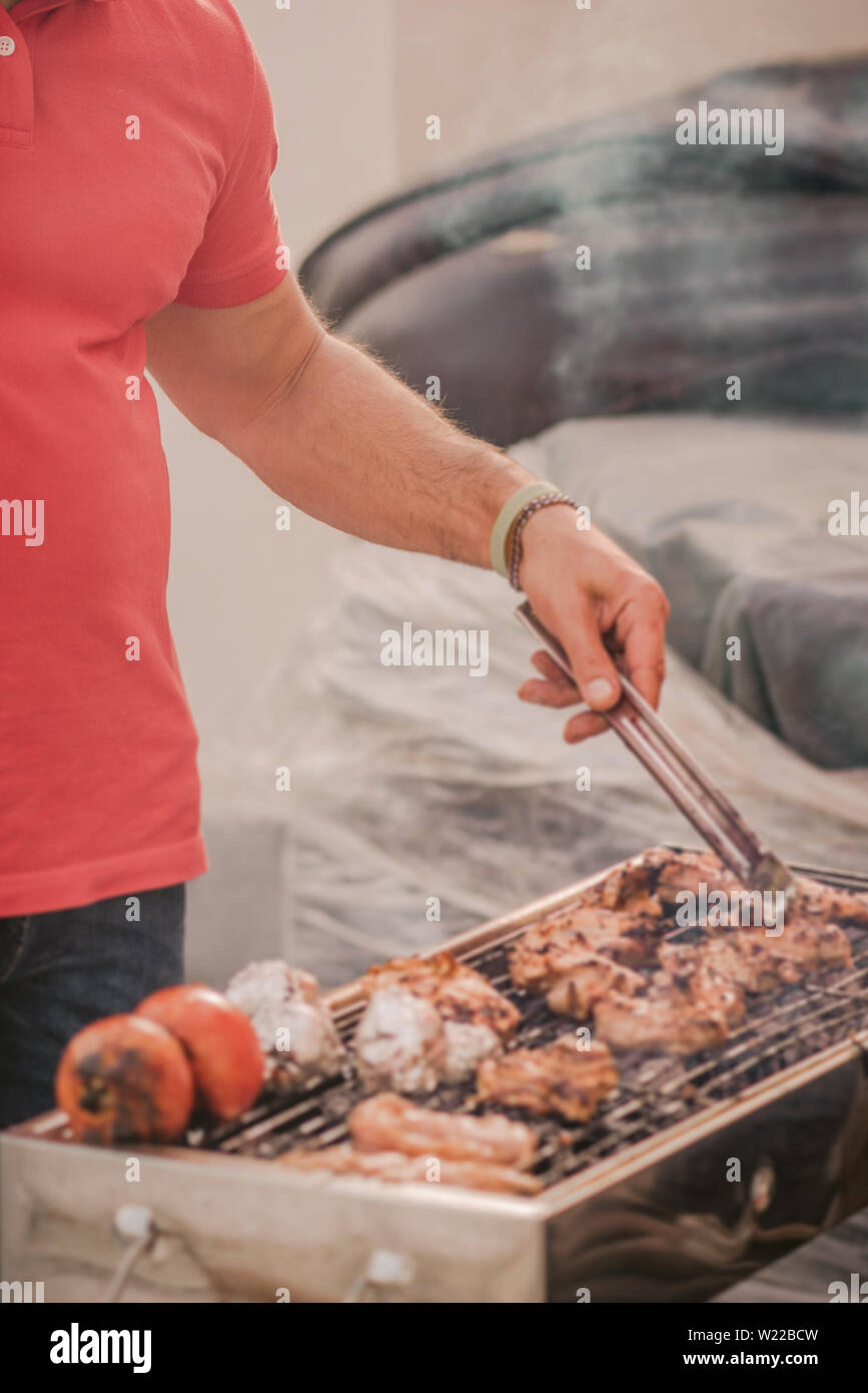 Handsome athletic man cooking barbecue outdoors. Brutal man with jeans ...