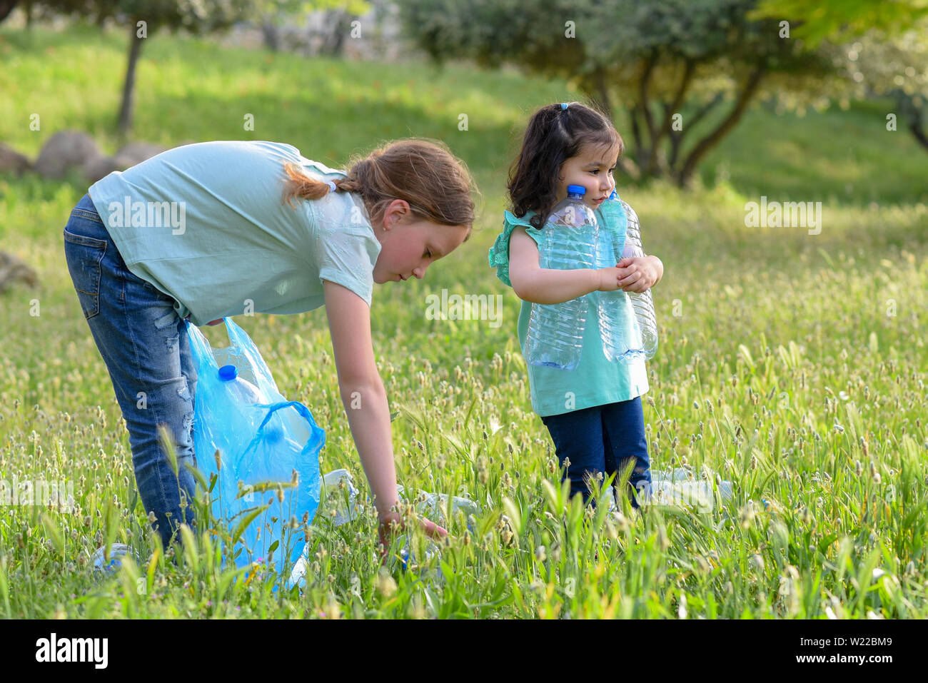 Two kids volunteer cleaning plastic pollution in summer park. Children ...