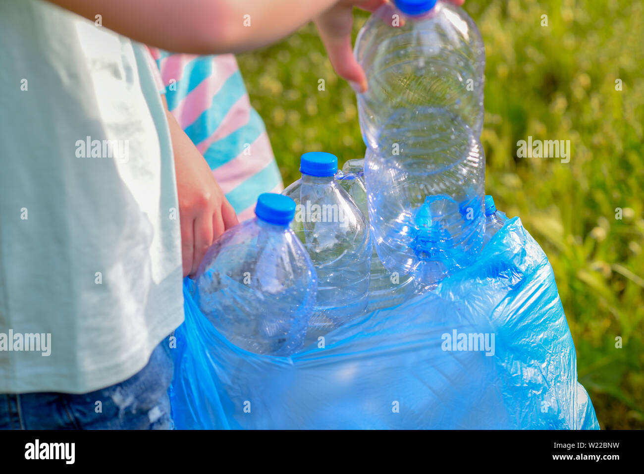 Kids cleaning in park.Close up hands volunteer child with a garbage bag ...